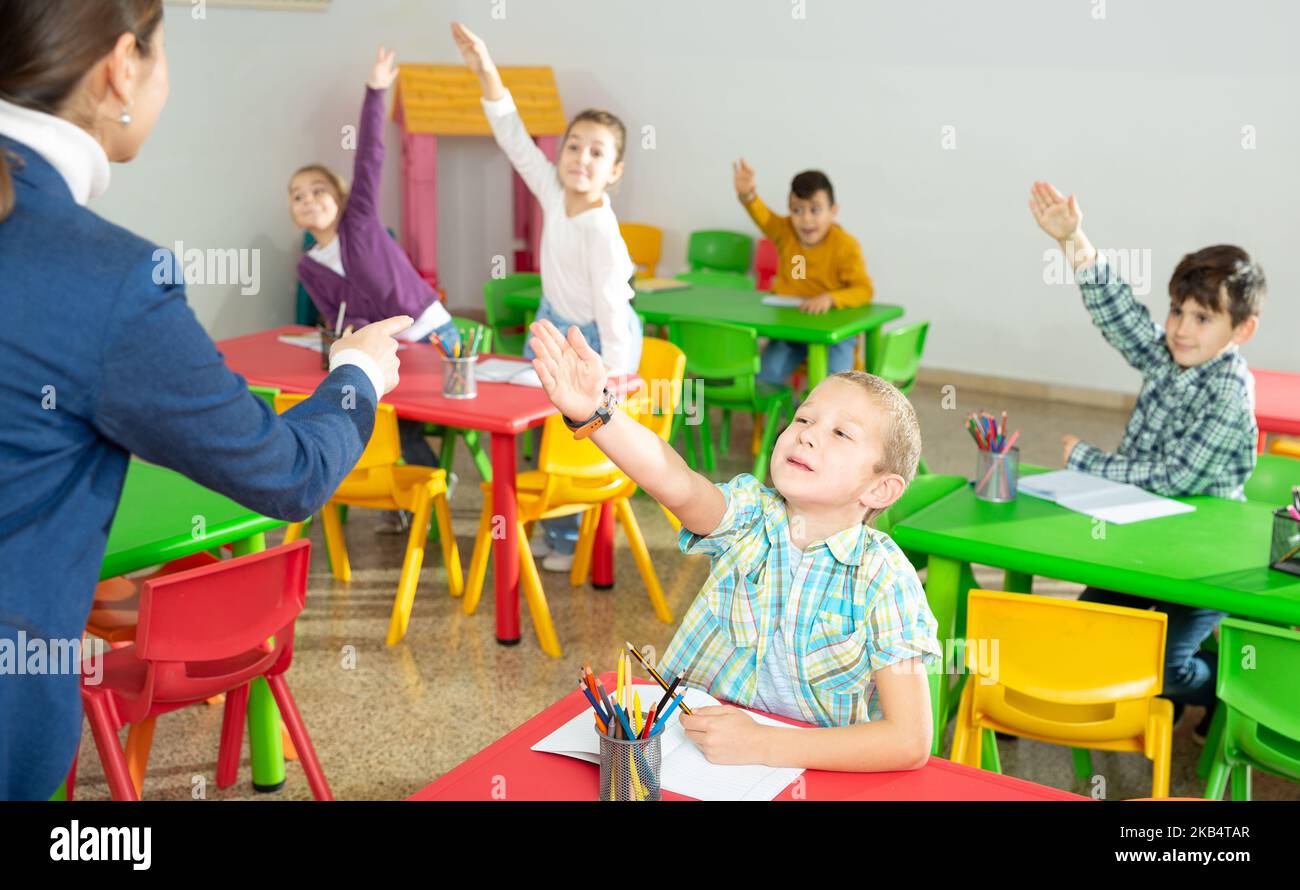 Children pull their hands to answer teacher question in the school ...