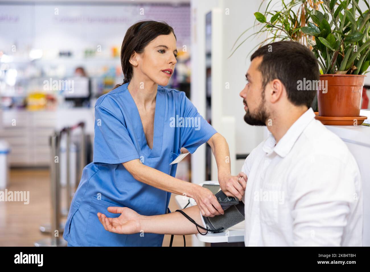 Female pharmacist checking blood pressure of customer Stock Photo - Alamy