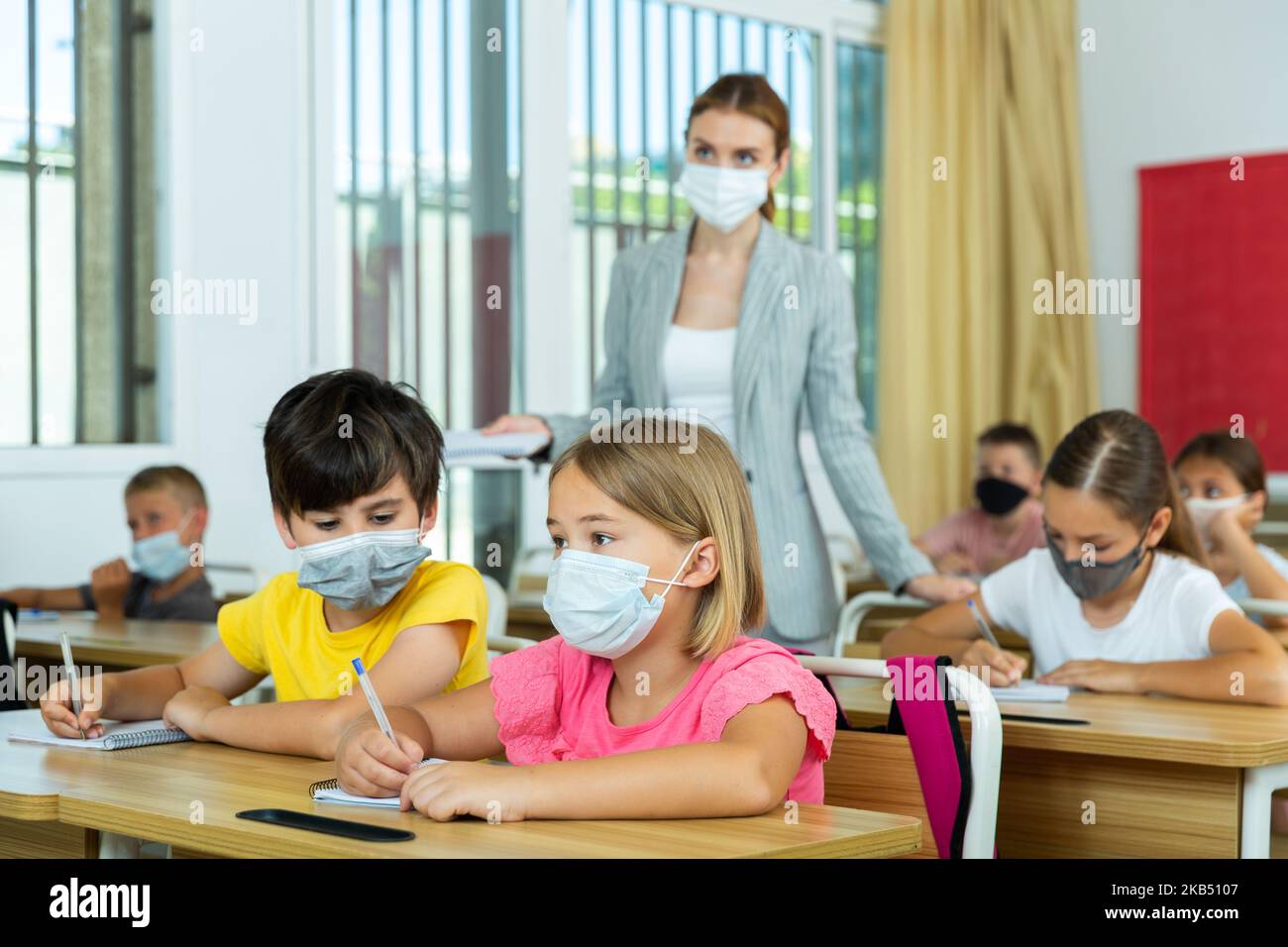Kids in masks studying in classroom Stock Photo - Alamy