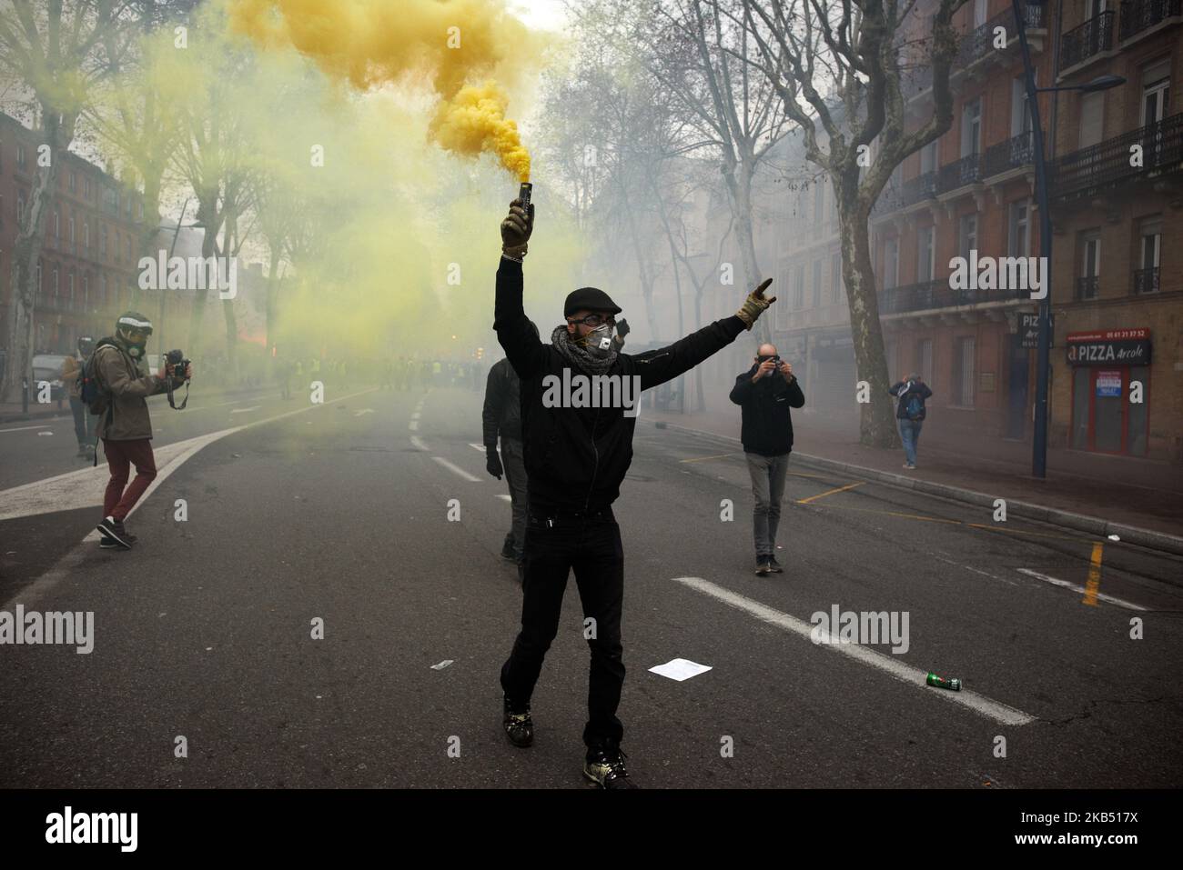A protester brandishes a yellow smoke amid clouds of tear gas. For the ...