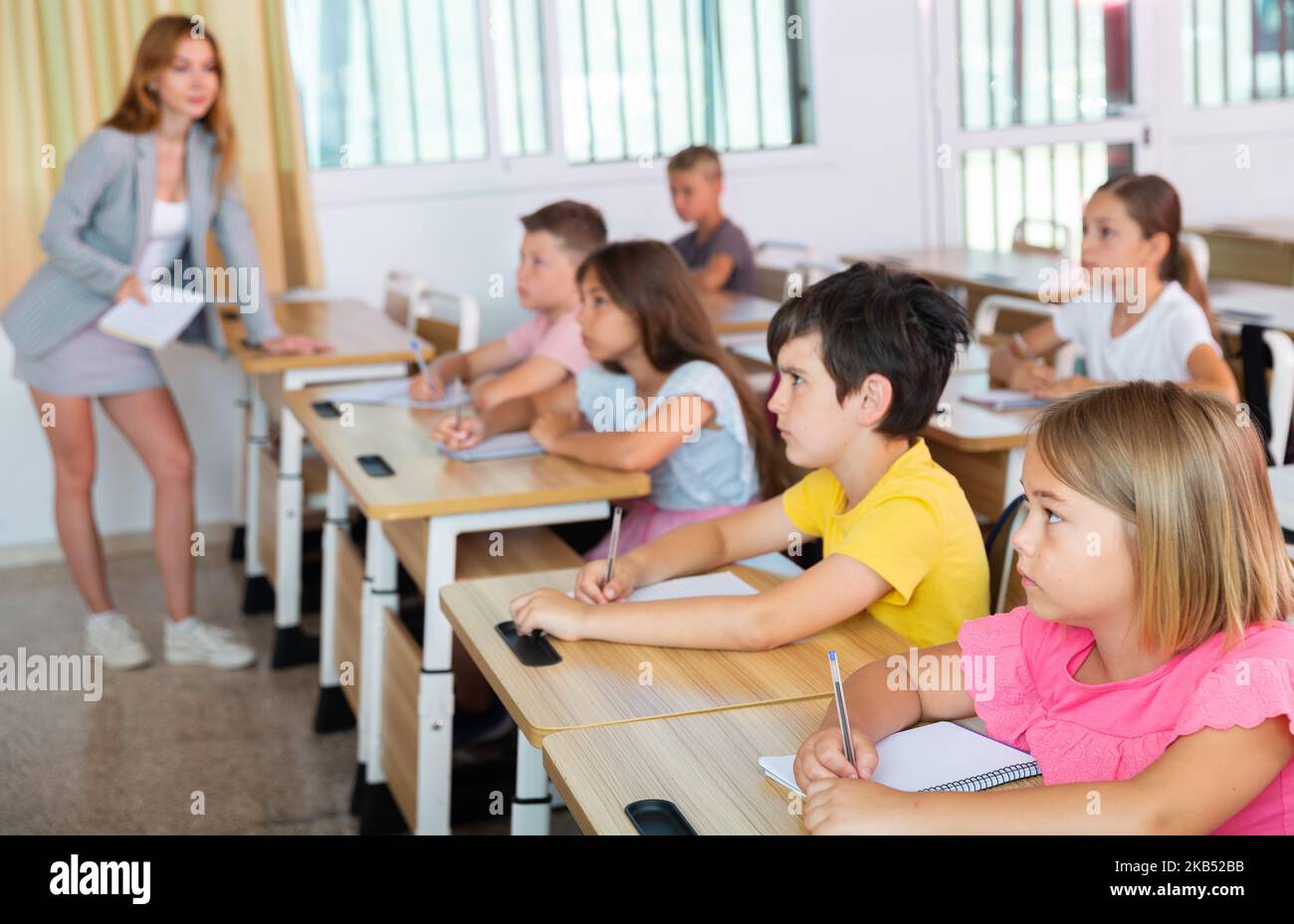 Kids listening to teacher Stock Photo - Alamy