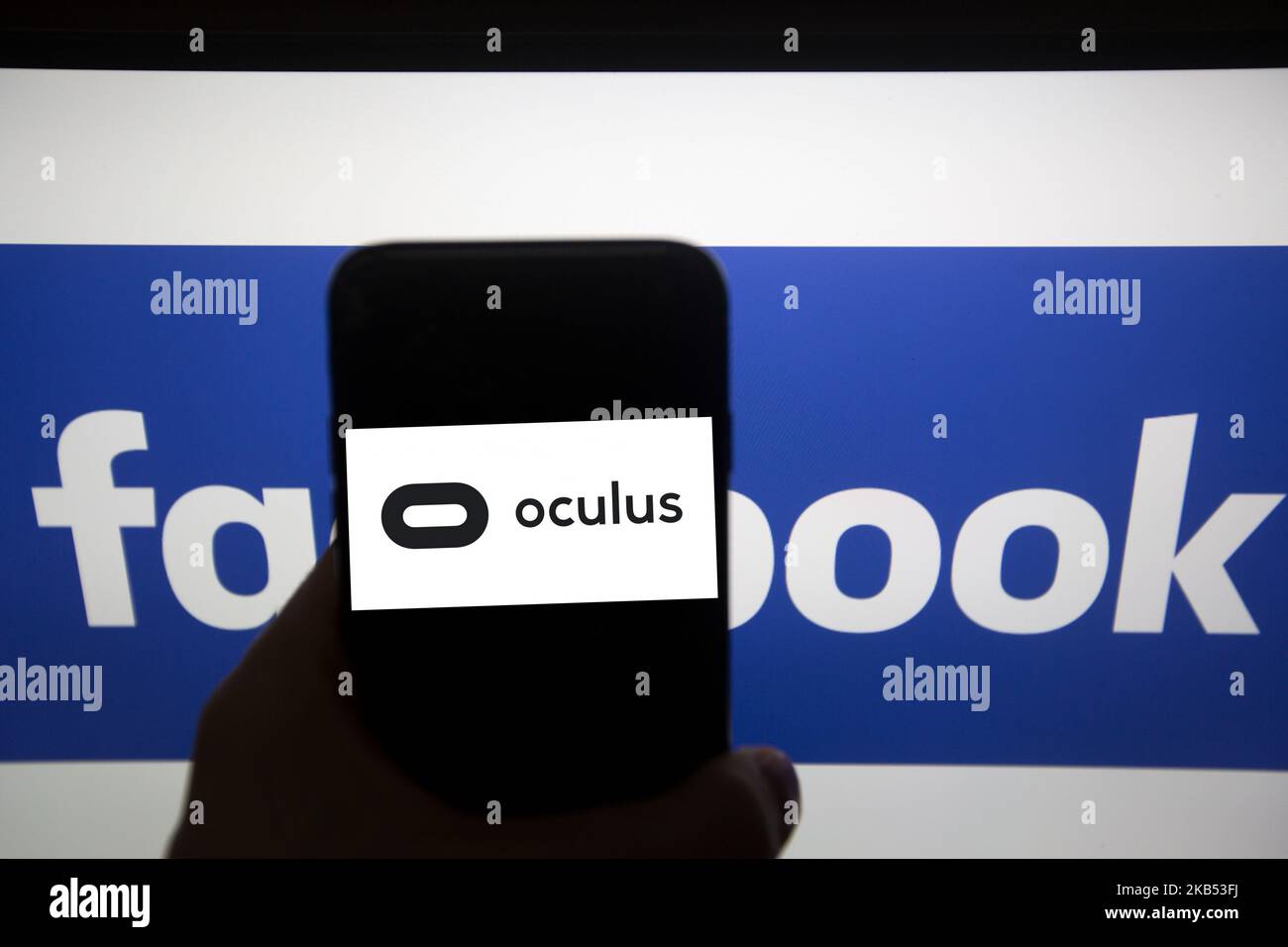 The logo of Oculus VR is seen on a smartphone in front of the logo of ...