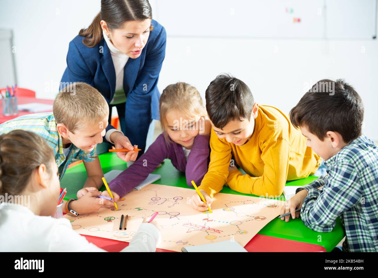 Pretty boys and girls with teacher draw a table game in classroom Stock ...