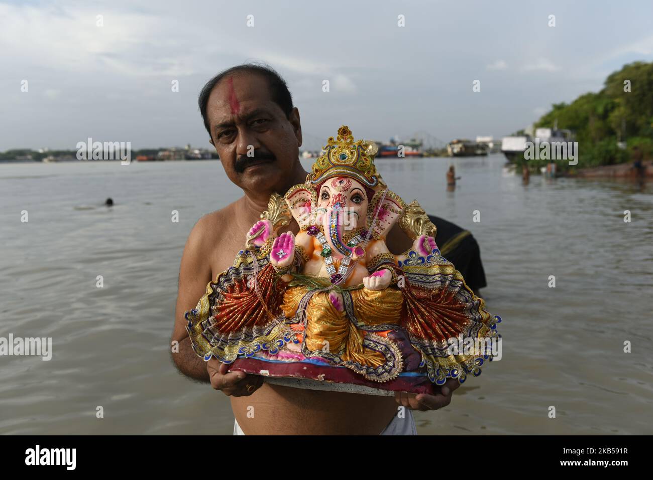 A devotee carries an idol of elephant-headed Hindu god Ganesha, for ...