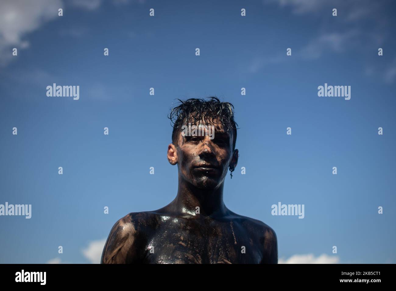 A man covered in black grease takes part in the traditional festival of ...