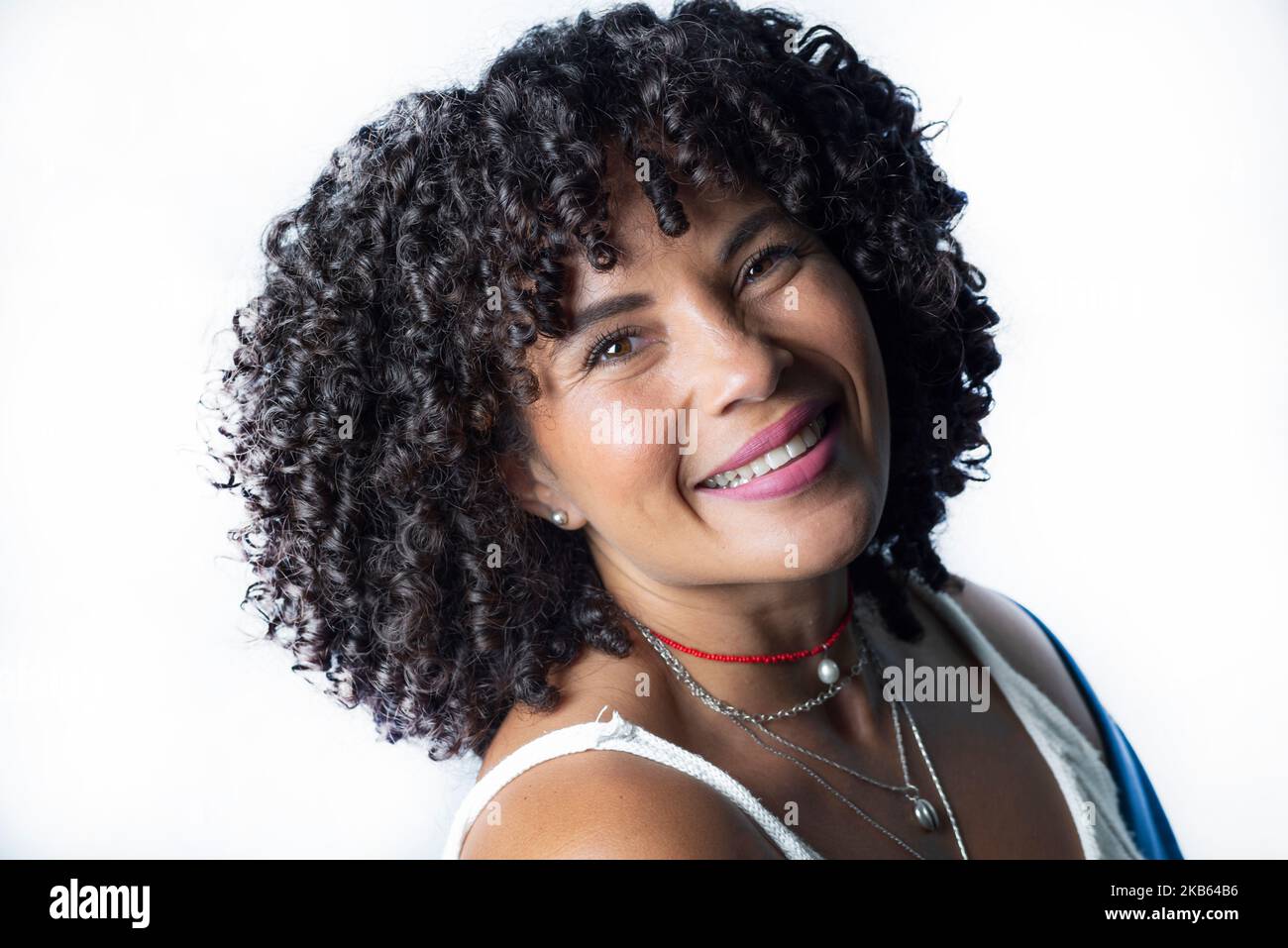Portrait of smiling beautiful curly hair model against light background ...