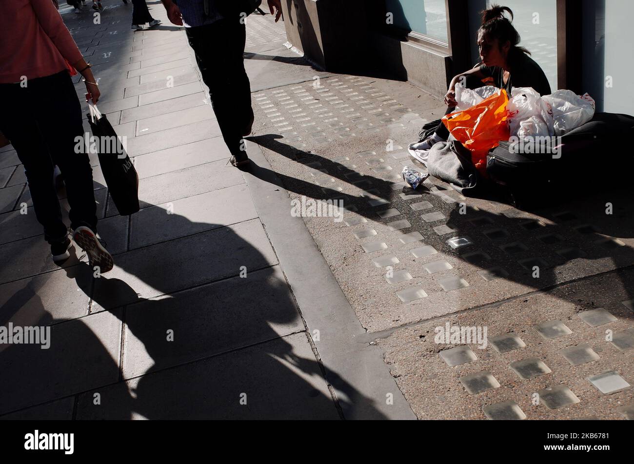 A homeless woman sits on the pavement of Oxford Street in London ...