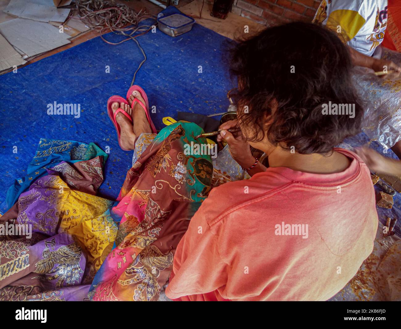 A woman batik artist creating various designs drawing with a pen-like ...