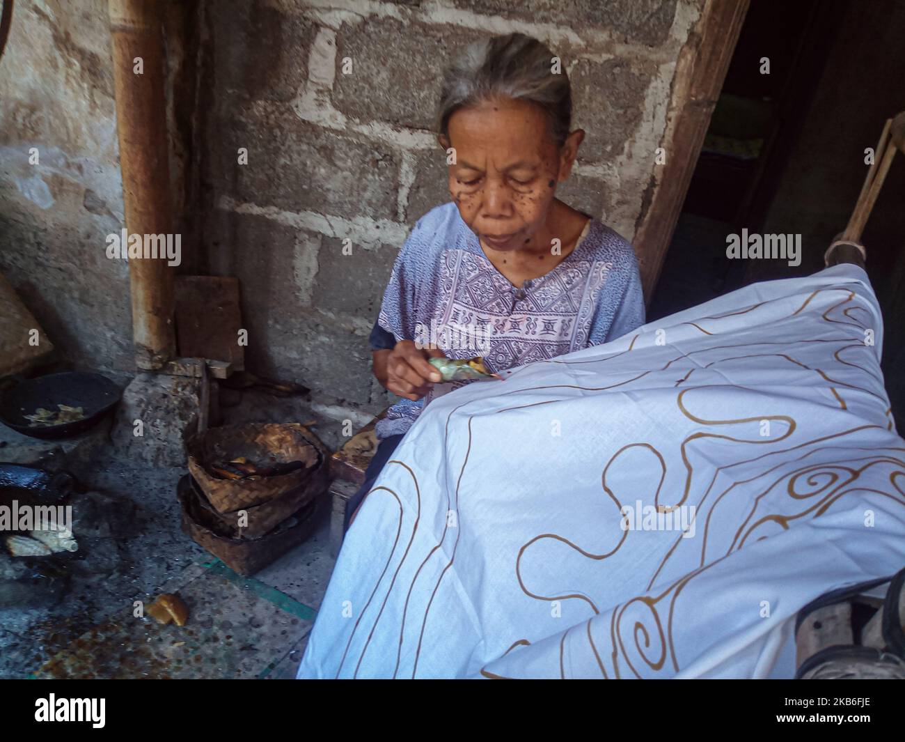 A woman batik artist creating various designs drawing with a pen-like ...