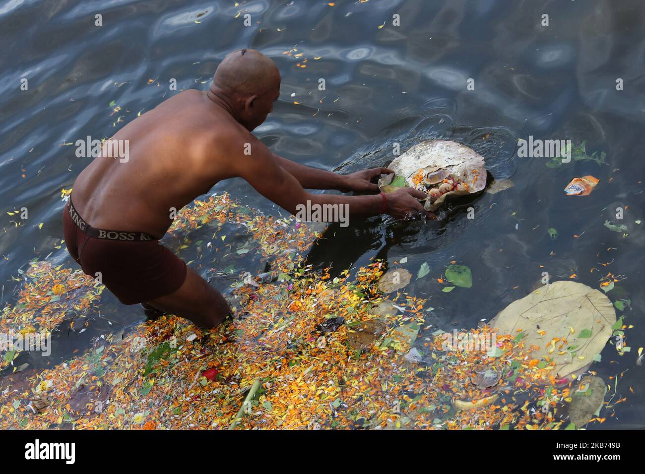 A devotee performs rituals on the banks of a holy pond on the occasion ...
