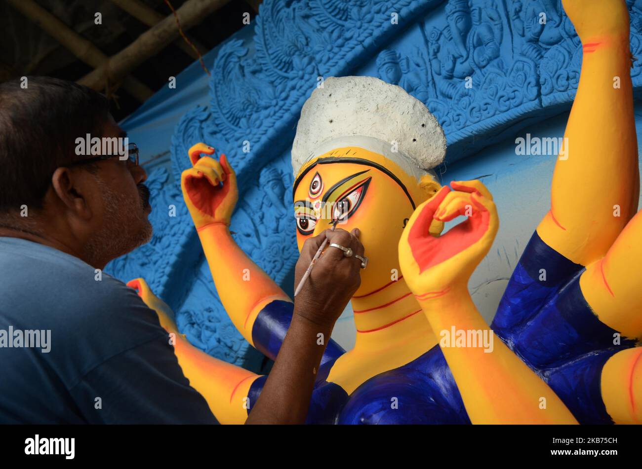 An Indian artisan gives the final touch on goddess Durga in a puja ...