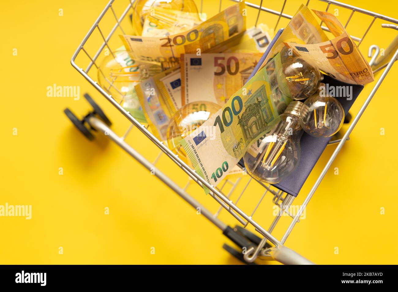 Electricity costs.Light bulbs and banknotes in a supermarket trolley on ...