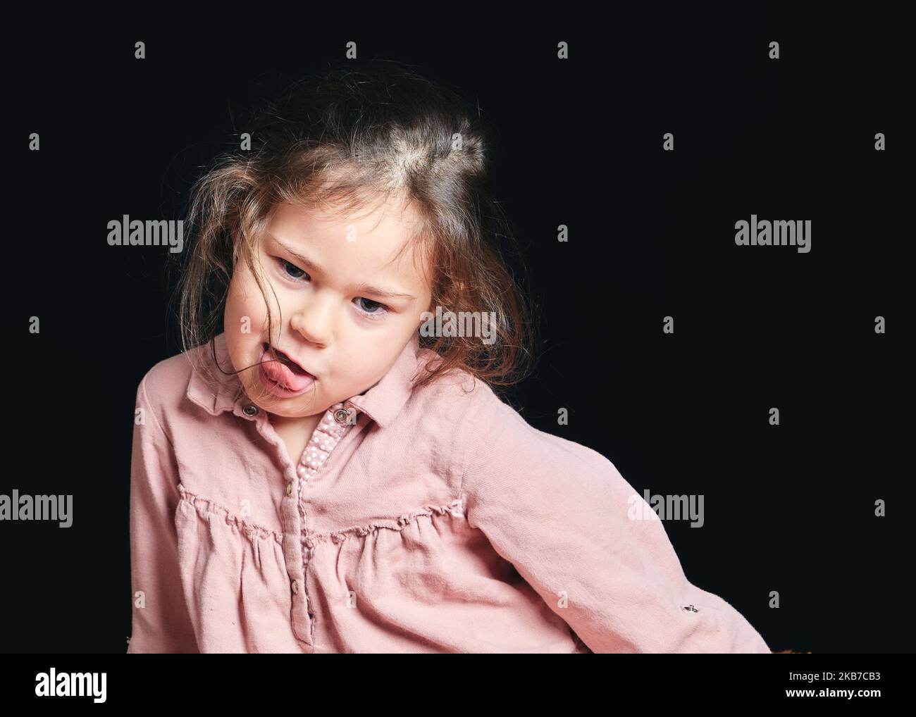 cute girl making expressive faces in the studio against a black ...