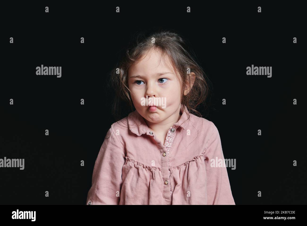 cute girl making expressive faces in the studio against a black ...