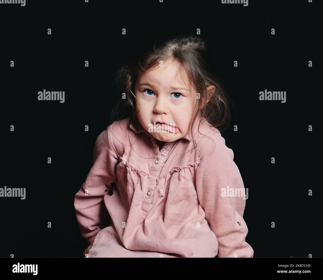 cute girl making expressive faces in the studio against a black ...