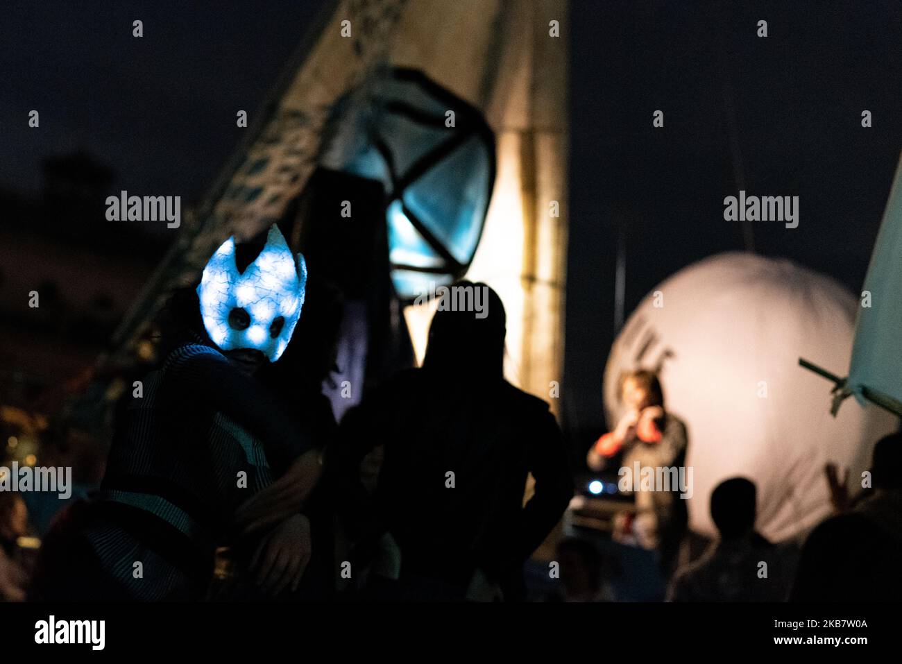 An environmental activist wearing a bright LED mask dances in front of ...