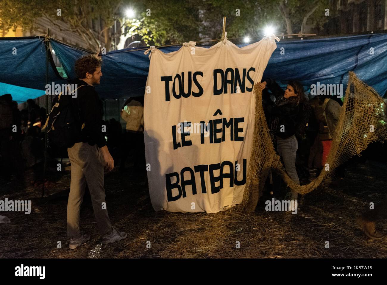 Environmental activists make shelter from the rain during the night ...
