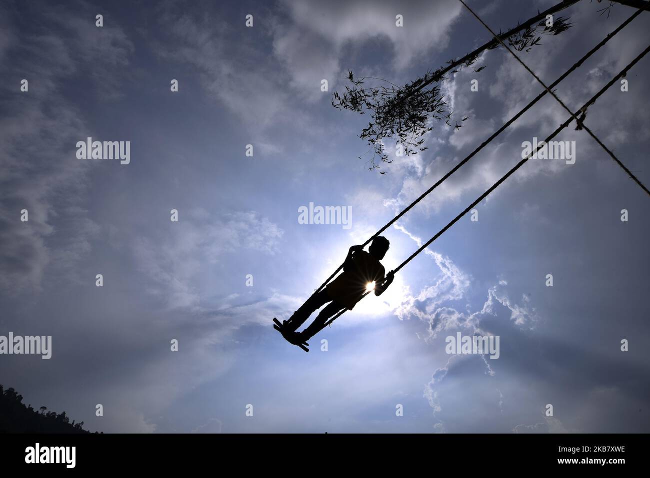 Nepalese youth plays on a traditional bamboo ping or swing during ...