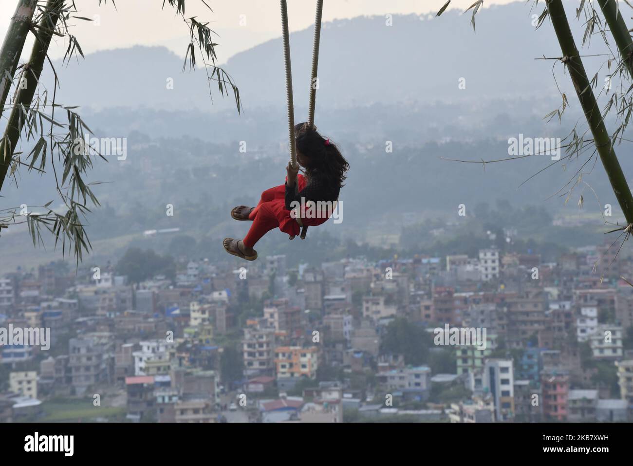 A Nepalese girl play on a traditional bamboo ping or swing during ...