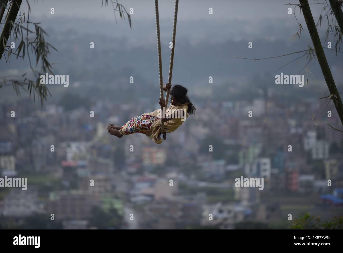 A Nepalese girl play on a traditional bamboo ping or swing during ...