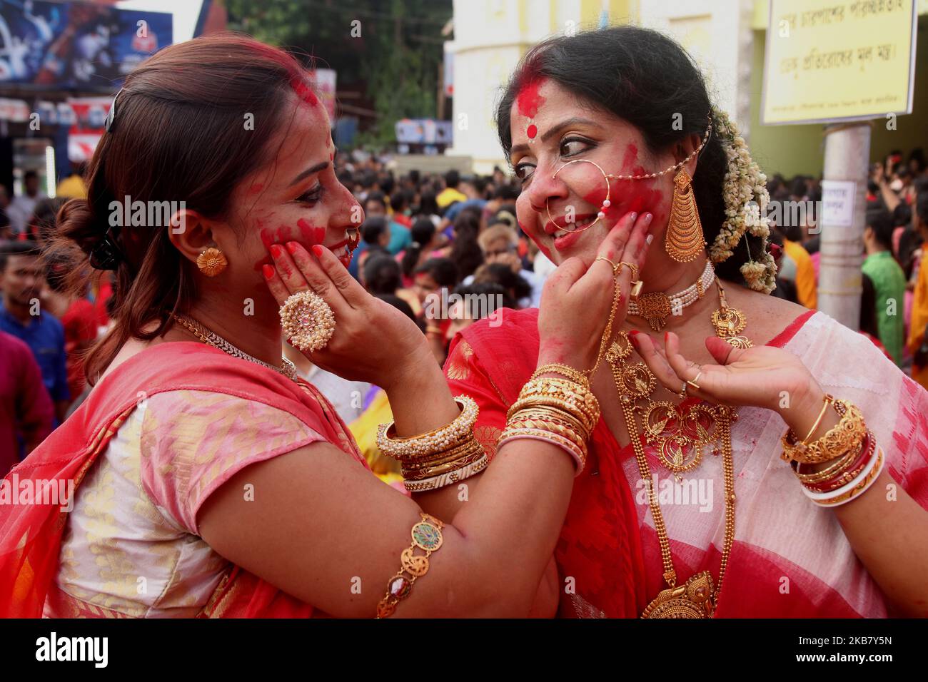 An Indian Hindu devotee smiles as she is smeared with vermillion powder ...