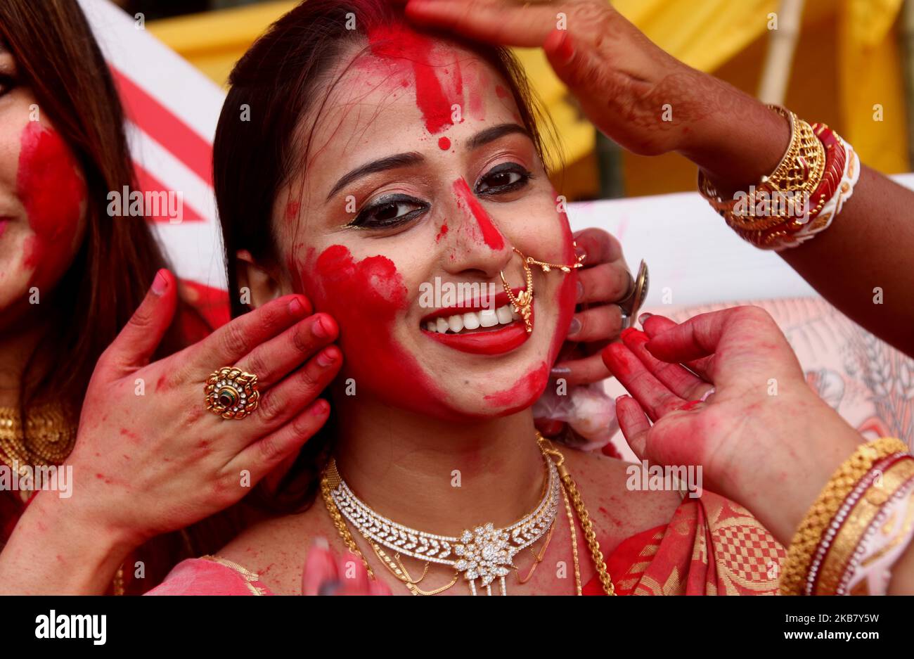 An Indian Hindu devotee smiles as she is smeared with vermillion powder ...