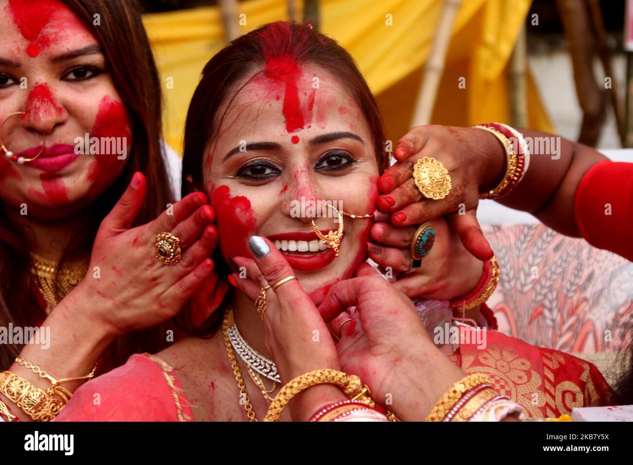 An Indian Hindu devotee smiles as she is smeared with vermillion powder ...