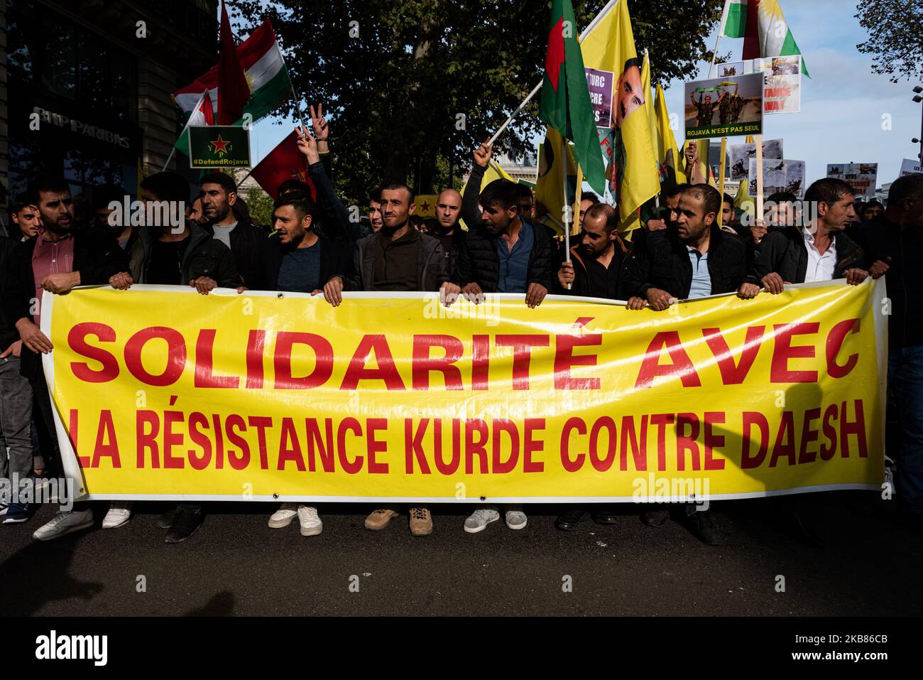 Kurdish demonstrators march behind a banner that reads "Solidarity with ...