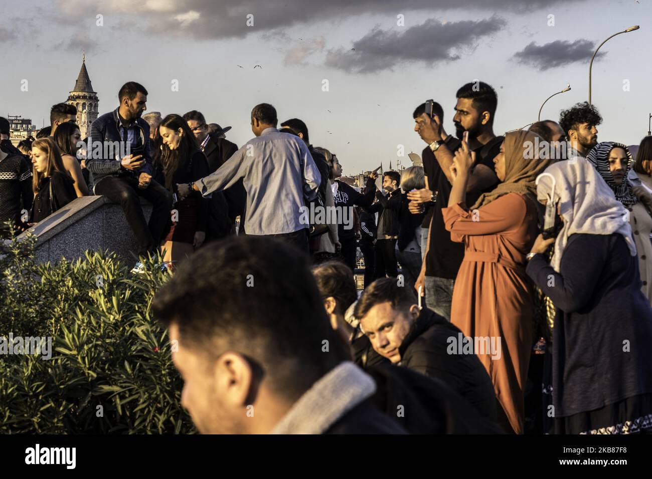 People take photo during the sunset on the Galata bridge in Istanbul on 13 October 2019 (Photo ...