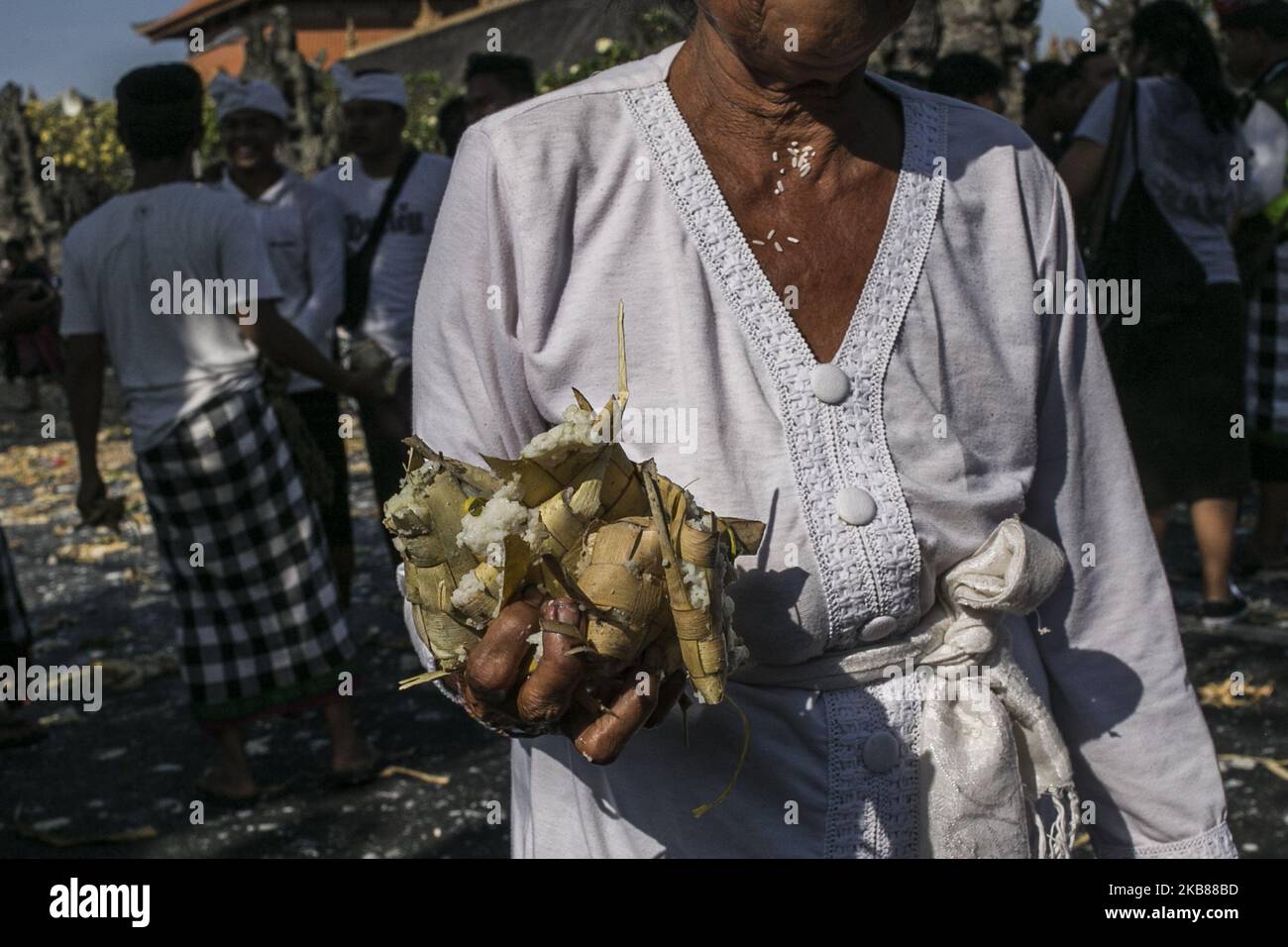Balinese Hindu collects the remaining tipat or square steamed rice wrap ...