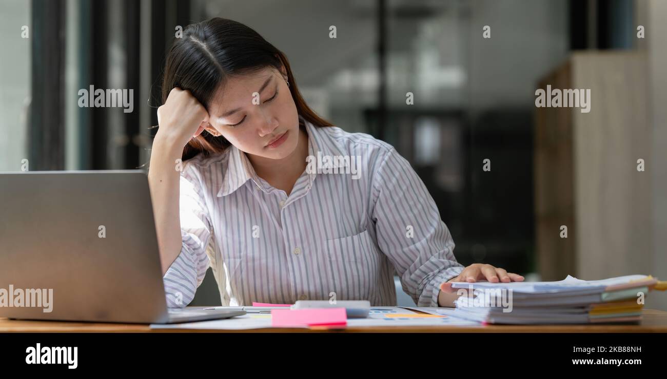 Stressed Asian business woman worry with many document on desk at ...