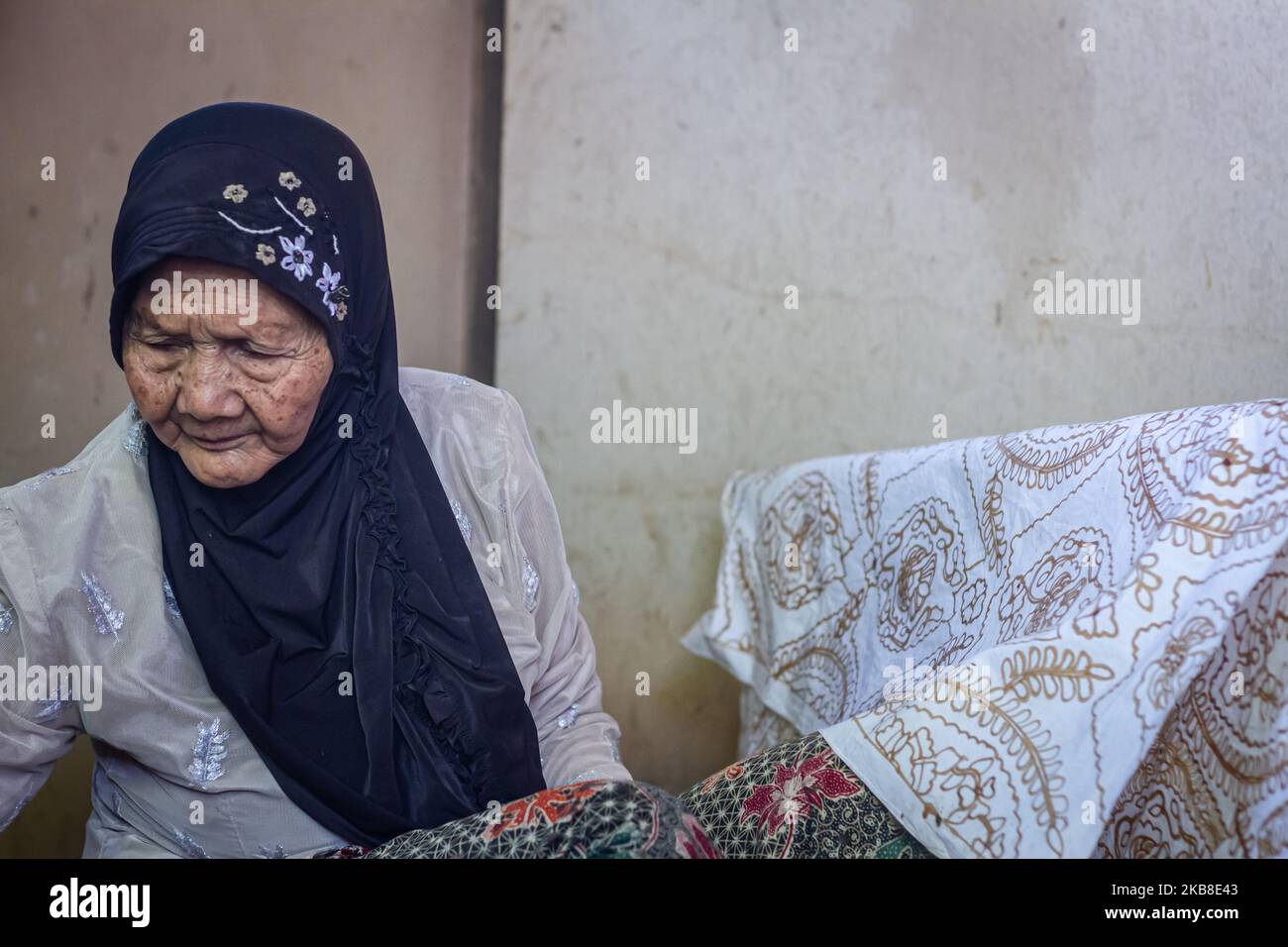 A woman batik artist creating various designs drawing with a pen-like ...