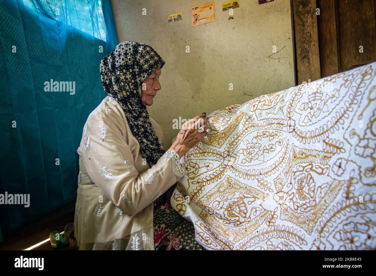 A woman batik artist creating various designs drawing with a pen-like ...
