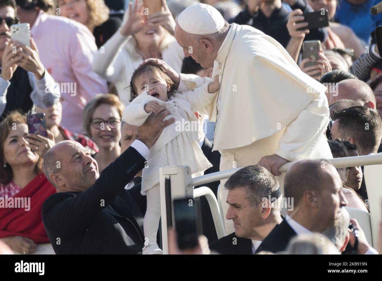 Pope Francis kisses a baby as he arrives for his weekly general ...