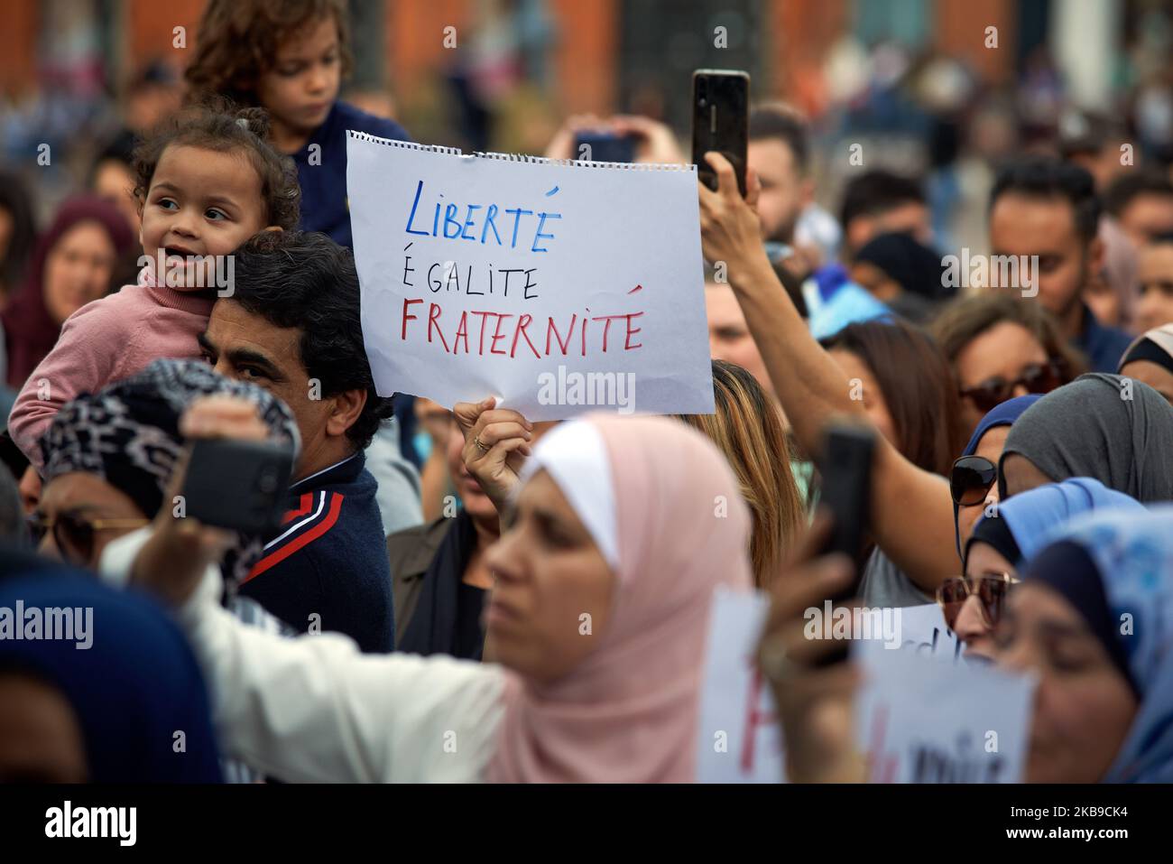 A placard reads 'Liberty, Equality, Fraternity'. People gathered ...