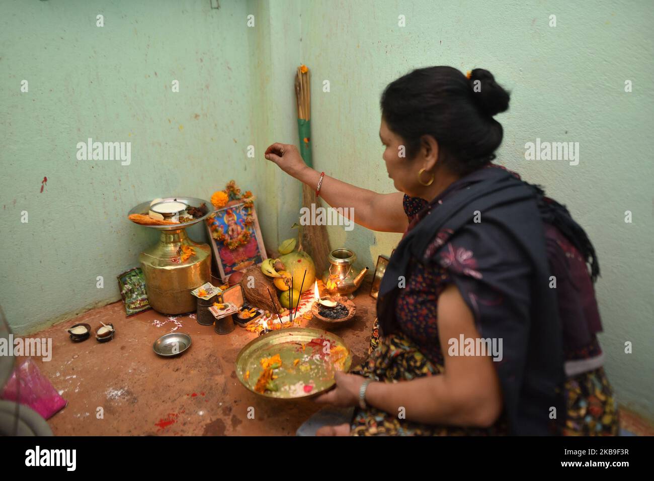A Nepalese devotee offering ritual prayer towards a poster of Laxmi ...