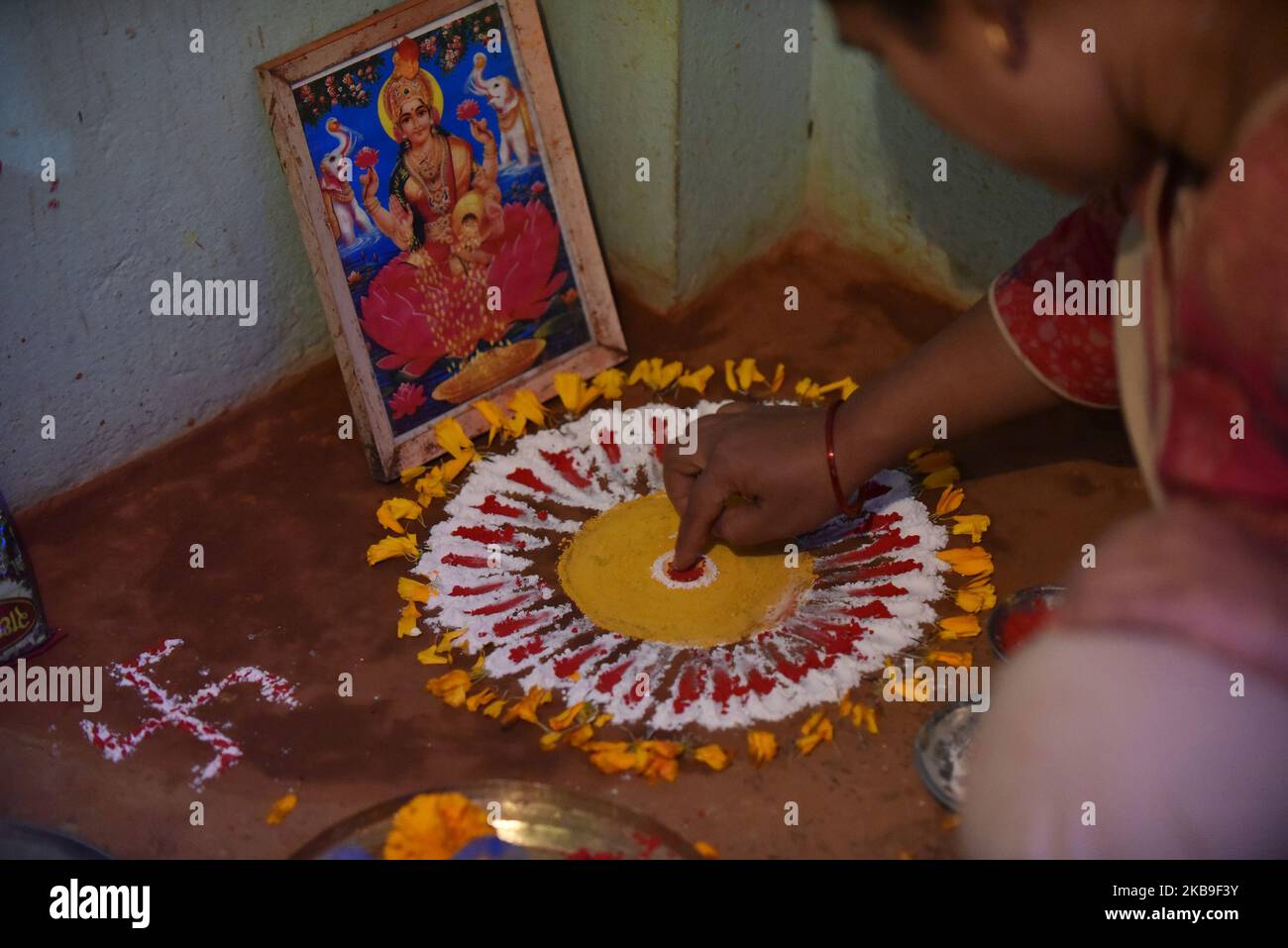 A Nepalese devotee offering ritual prayer towards a poster of Laxmi ...