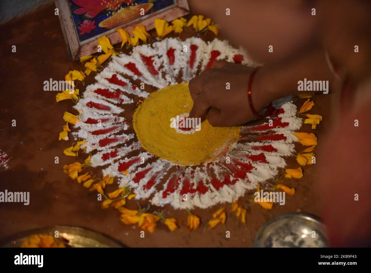 A Nepalese devotee offering ritual prayer towards a poster of Laxmi ...
