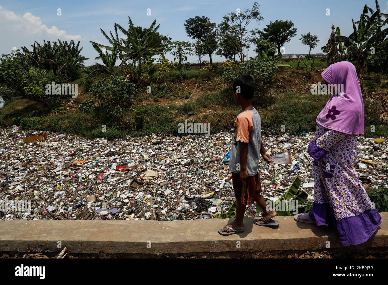 Children walk beside a river covered by garbage in Bekasi, West Java ...