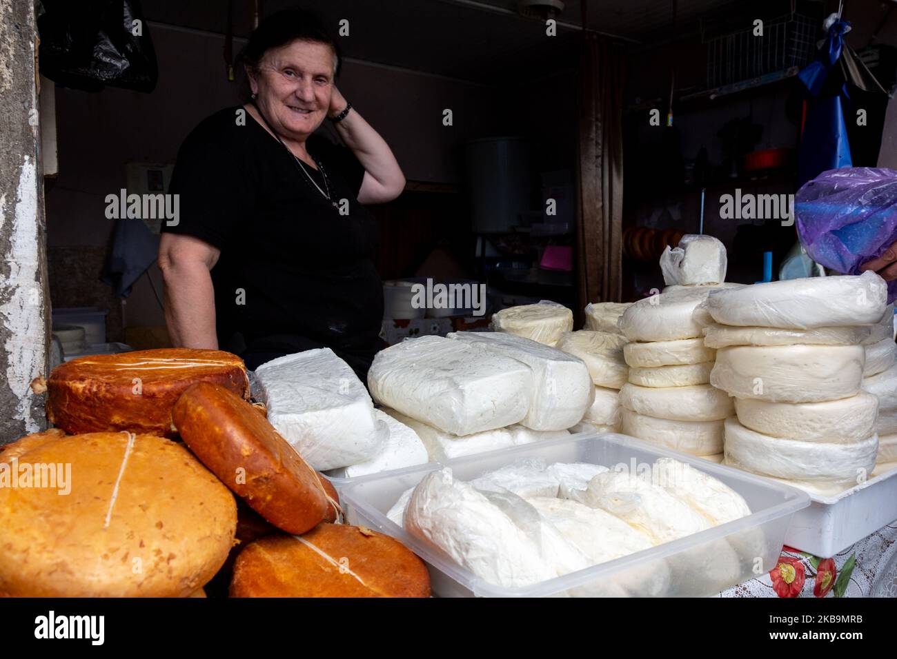 A woman sells hand made cheese on her small stand on the town's open ...