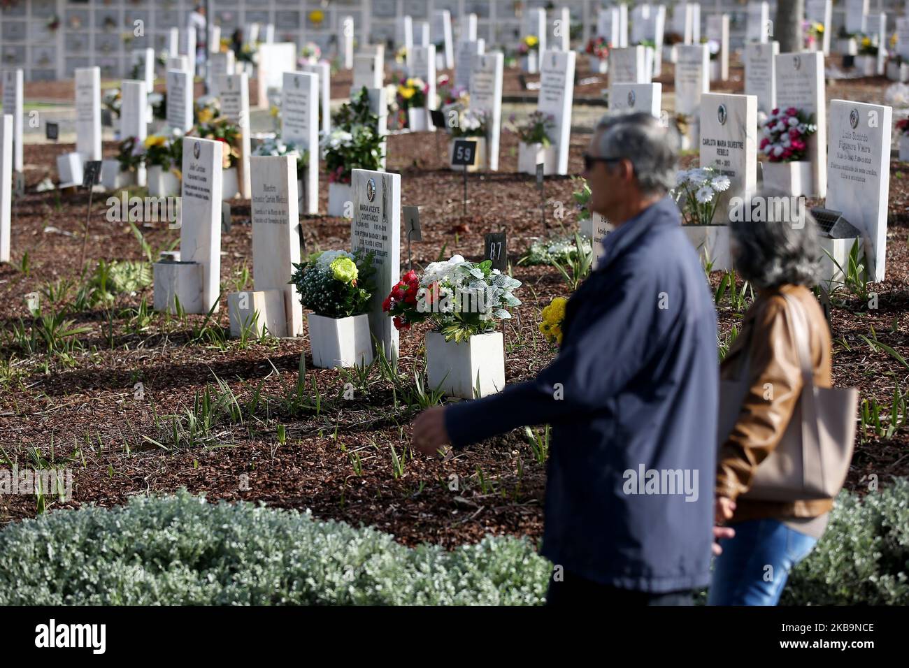 People walk past graves at a cemetery during the annual observance of ...