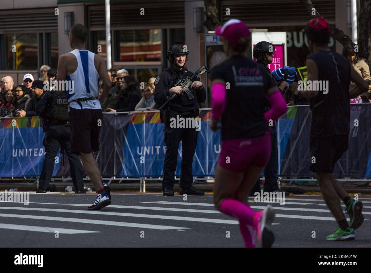 An armed NYPD officer watches the New York City Marathon Sunday ...