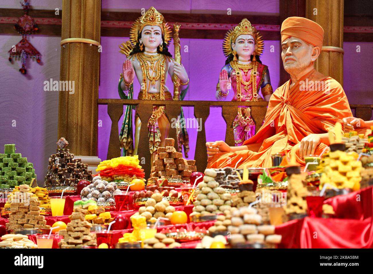 Mountains of sweets and vegetarian snacks are displayed in front of the ...