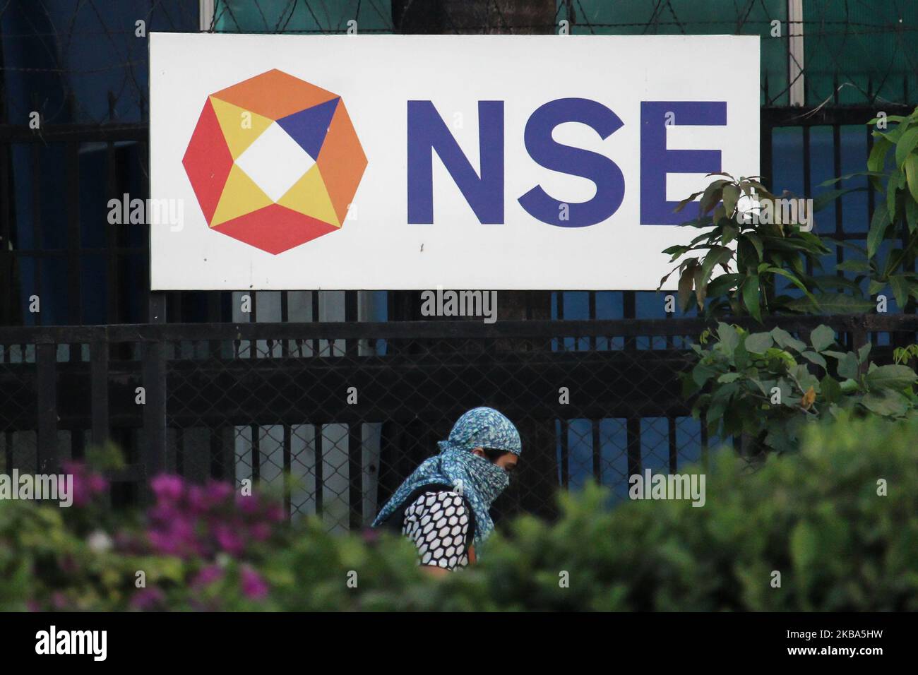 A woman walks past the logo of National Stock Exchange (NSE), outside ...