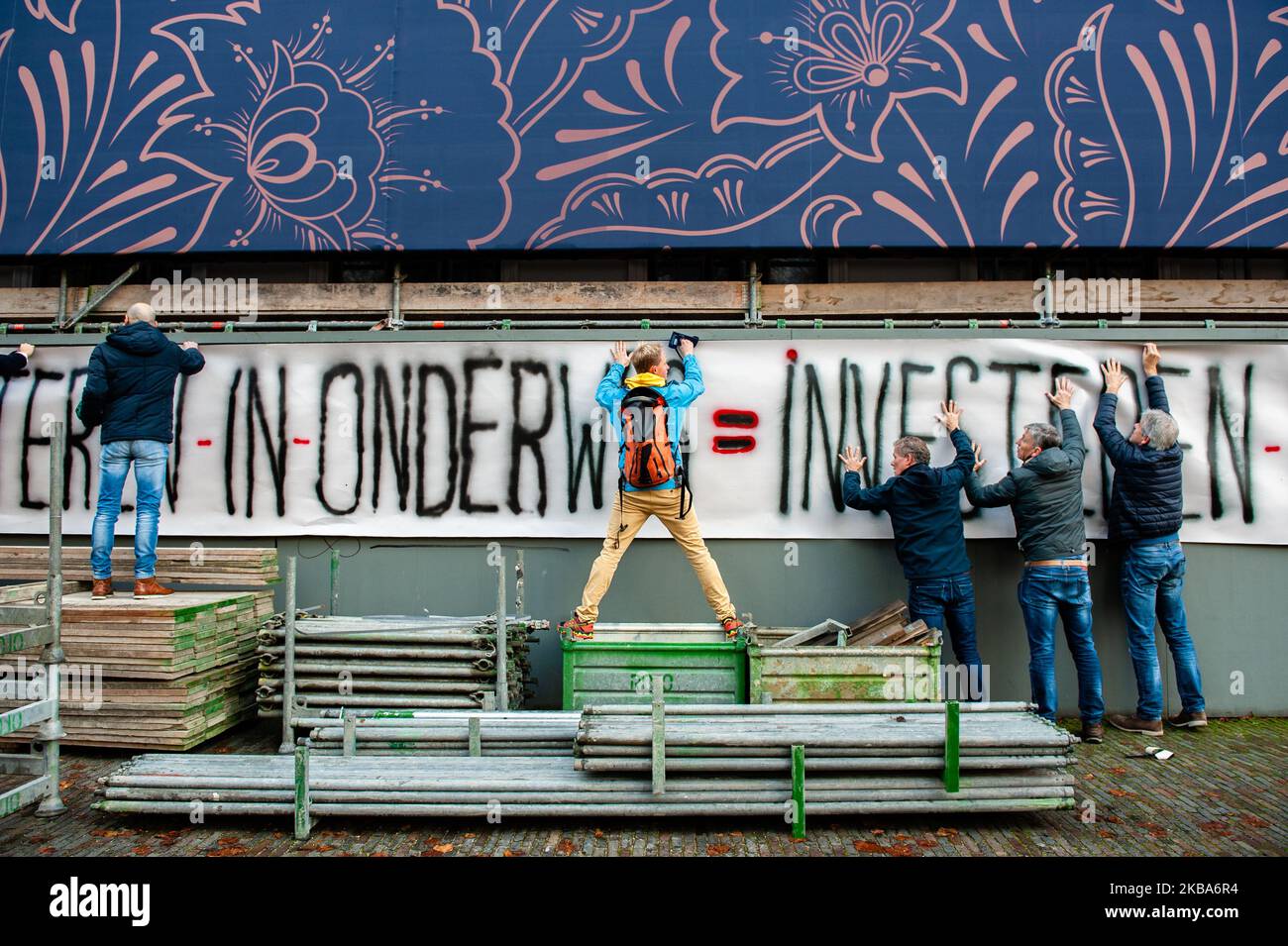 A group of teachers are seen holding a very big banner on a wall during ...