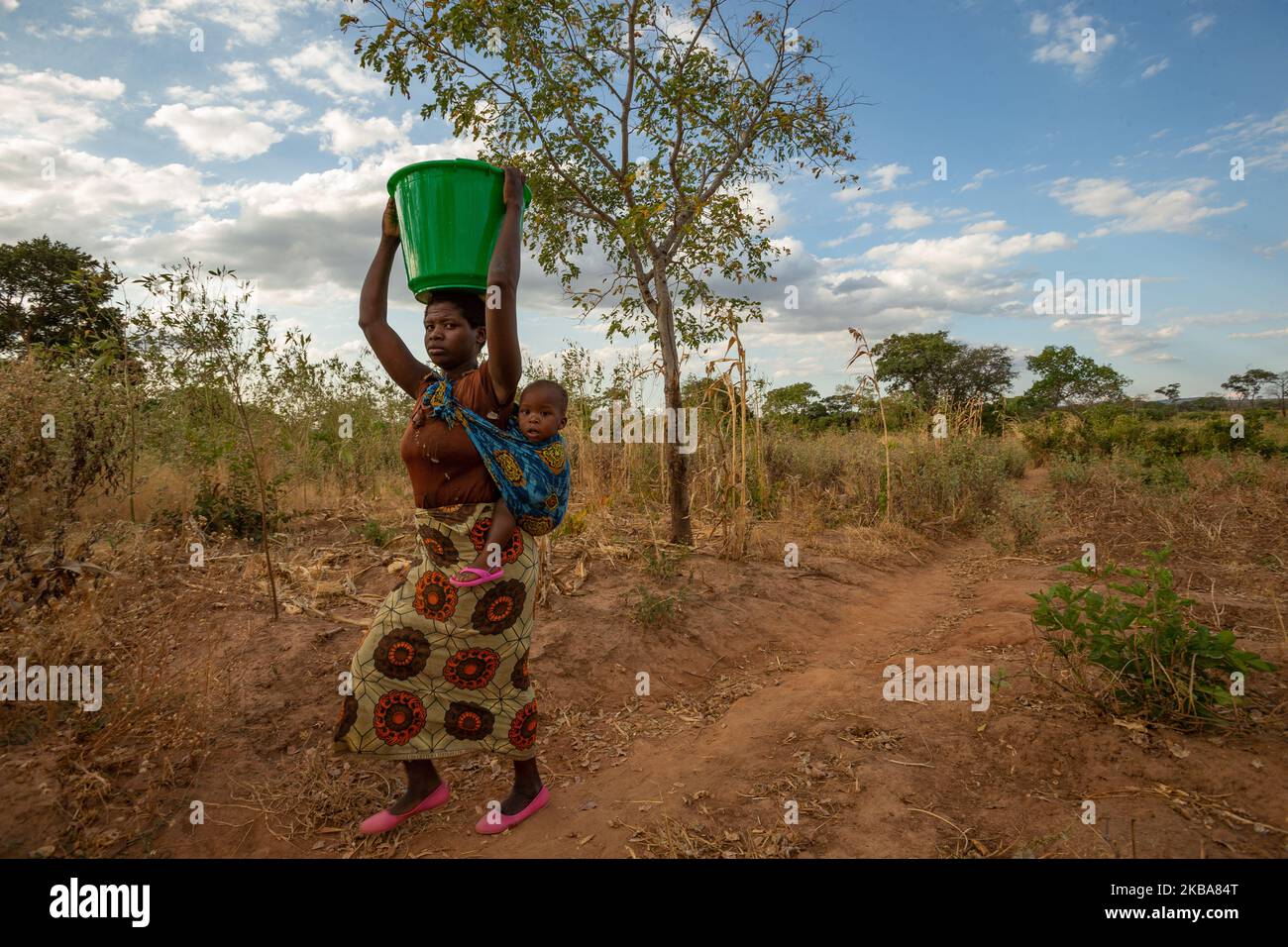 A woman carries water from a donated well, built by the organization ...
