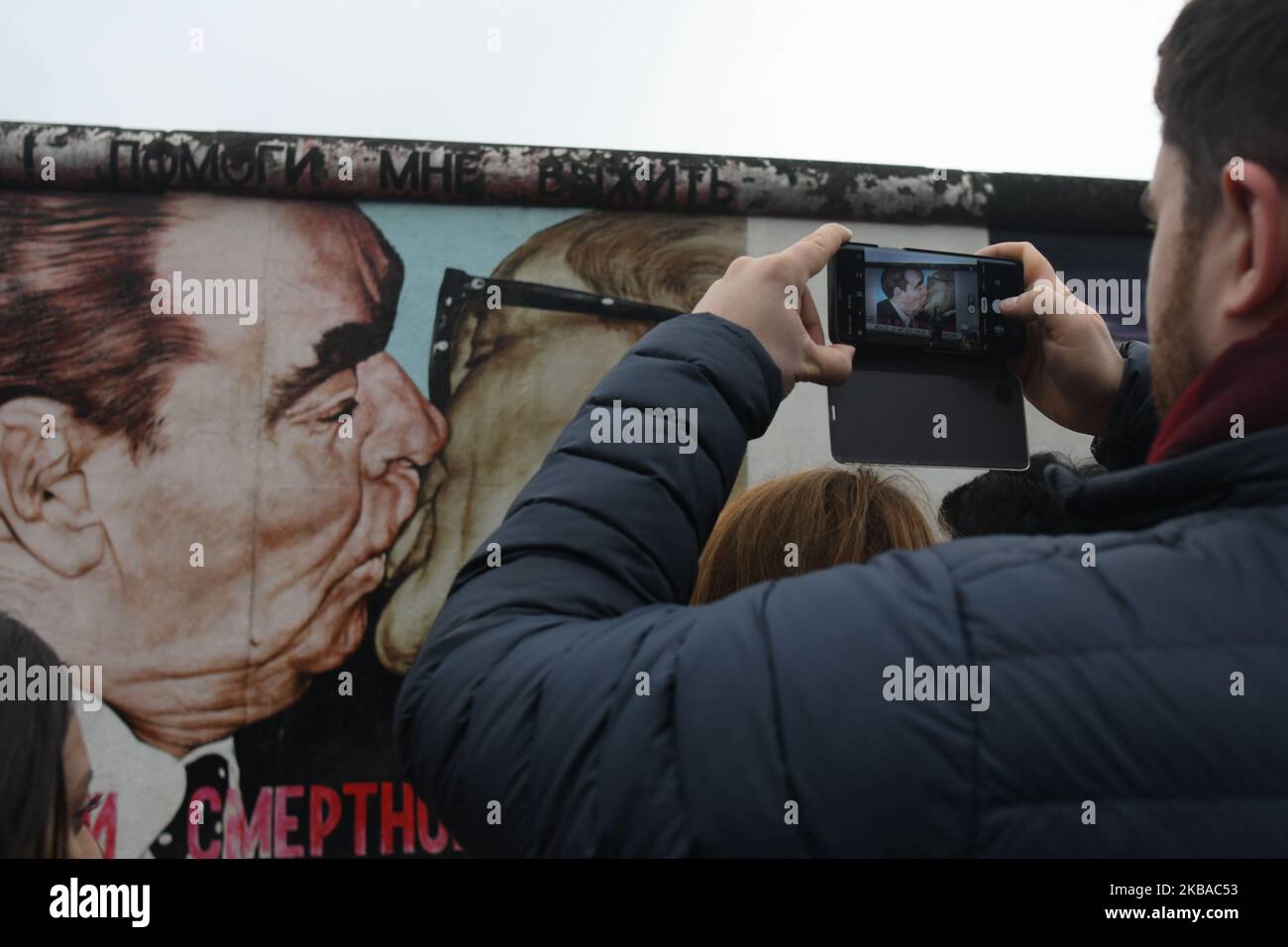 A visitor takes a picture of a mural by Russian artist Dmitri Vrubel ...