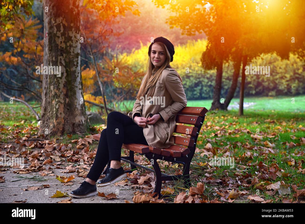 Young girl sitting on bench in public park at autumn. Girl wearing ...
