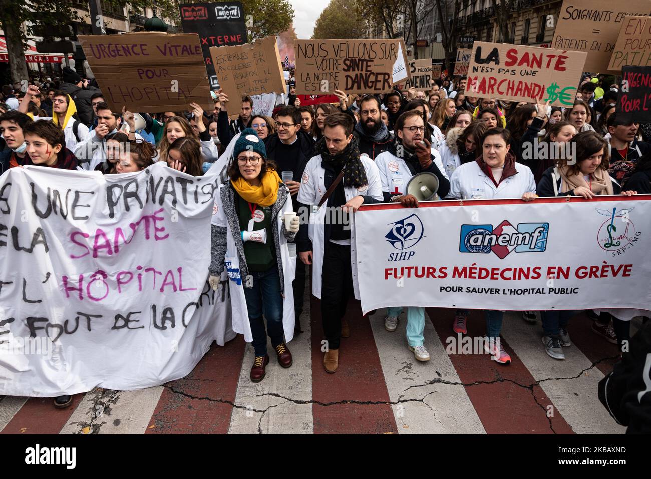 Many hospital staff dressed in white coats are demonstrating with signs ...