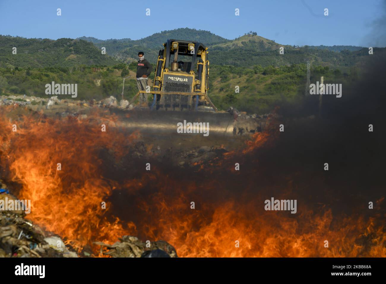 Officers use heavy equipment to separate burning rubbish at the ...